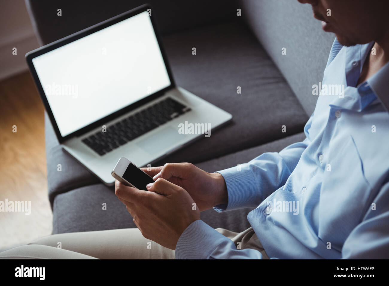 Man using mobile phone in living room Stock Photo - Alamy