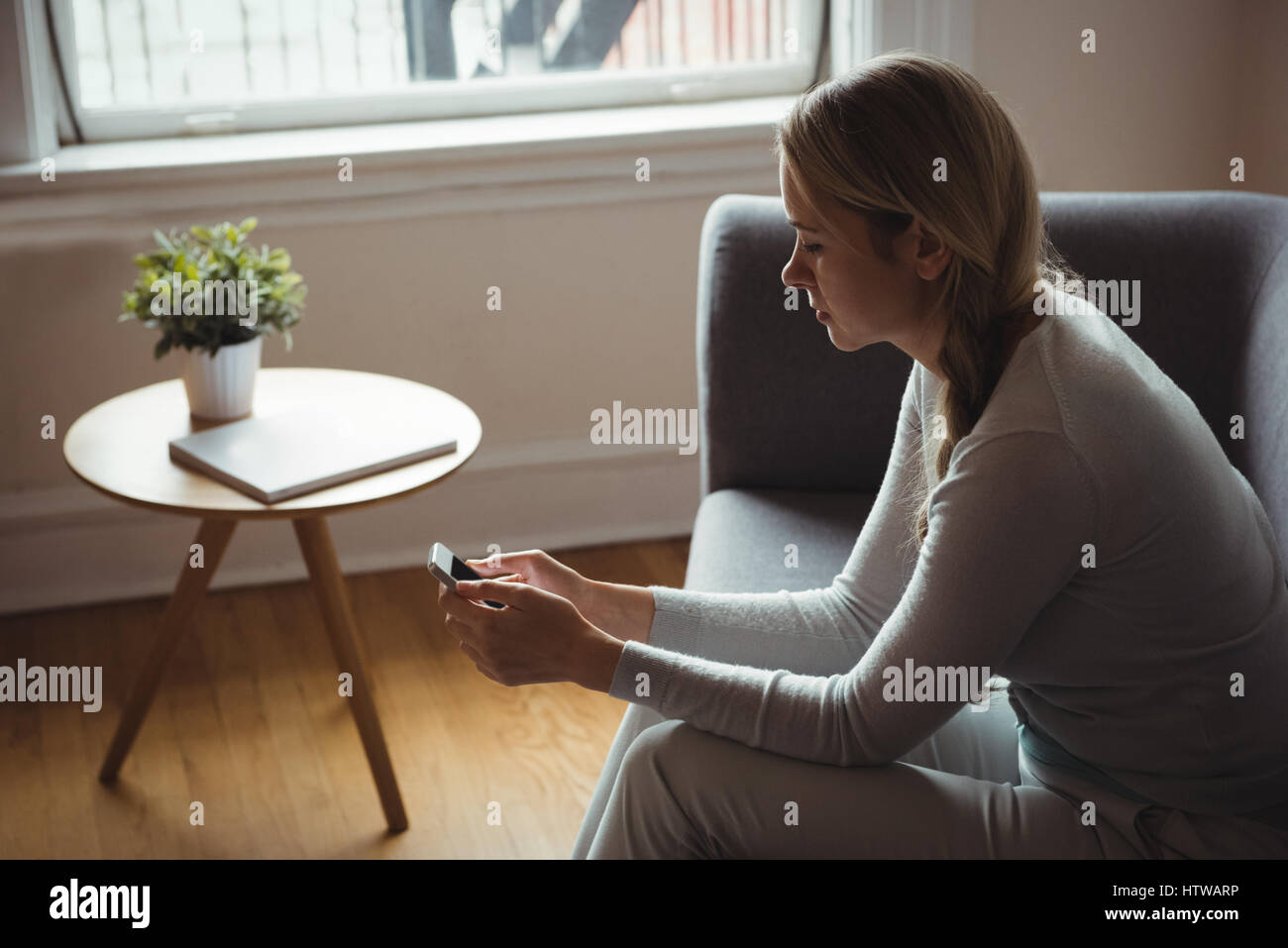 Woman using mobile phone in living room Stock Photo - Alamy