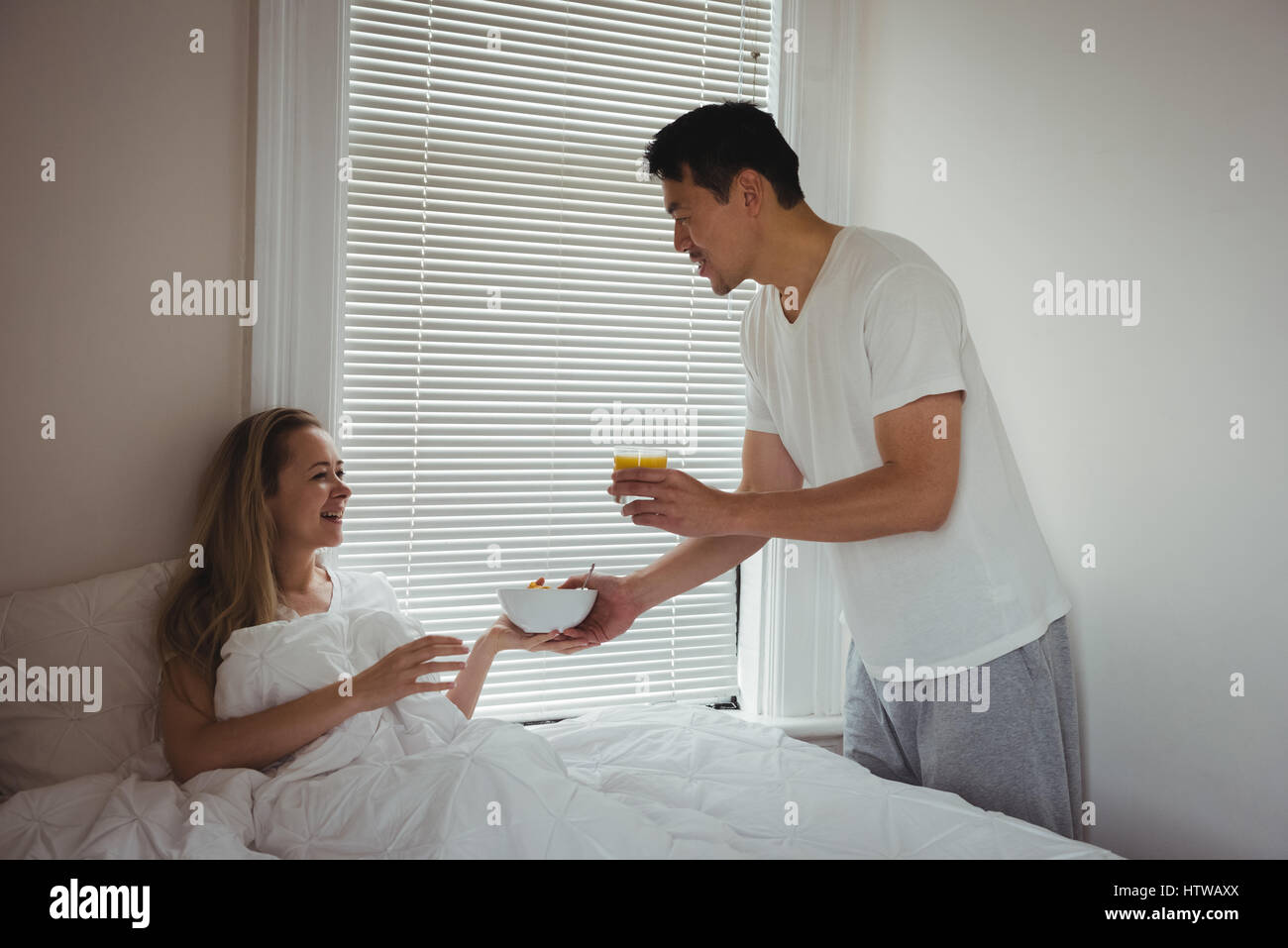 Man serving breakfast to woman in bedroom Stock Photo - Alamy