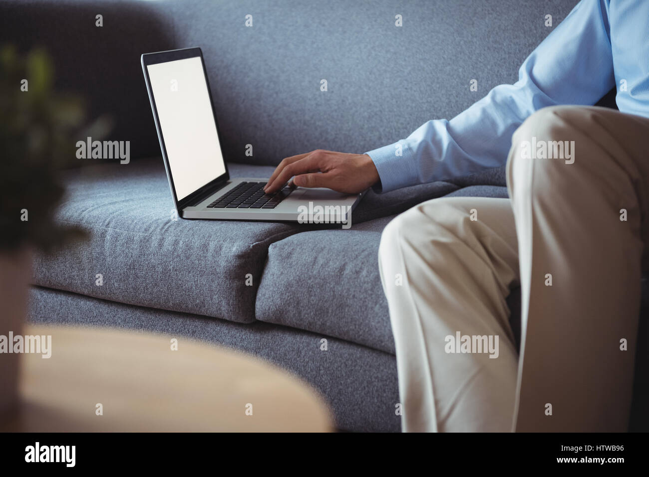 Mid section of man using laptop in living room Stock Photo - Alamy