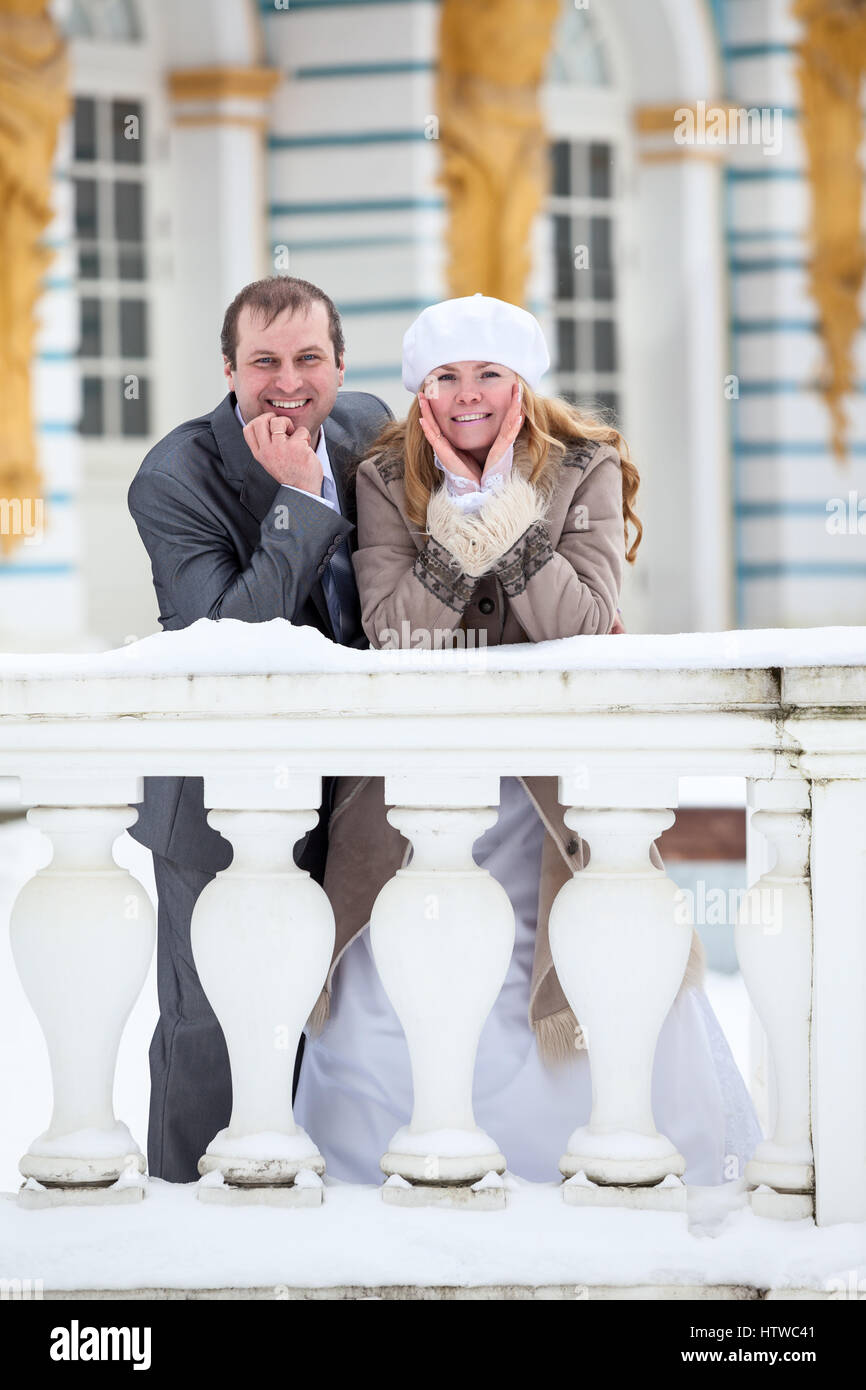 Happy and smiling man and woman standing behind balustrade, winter ...