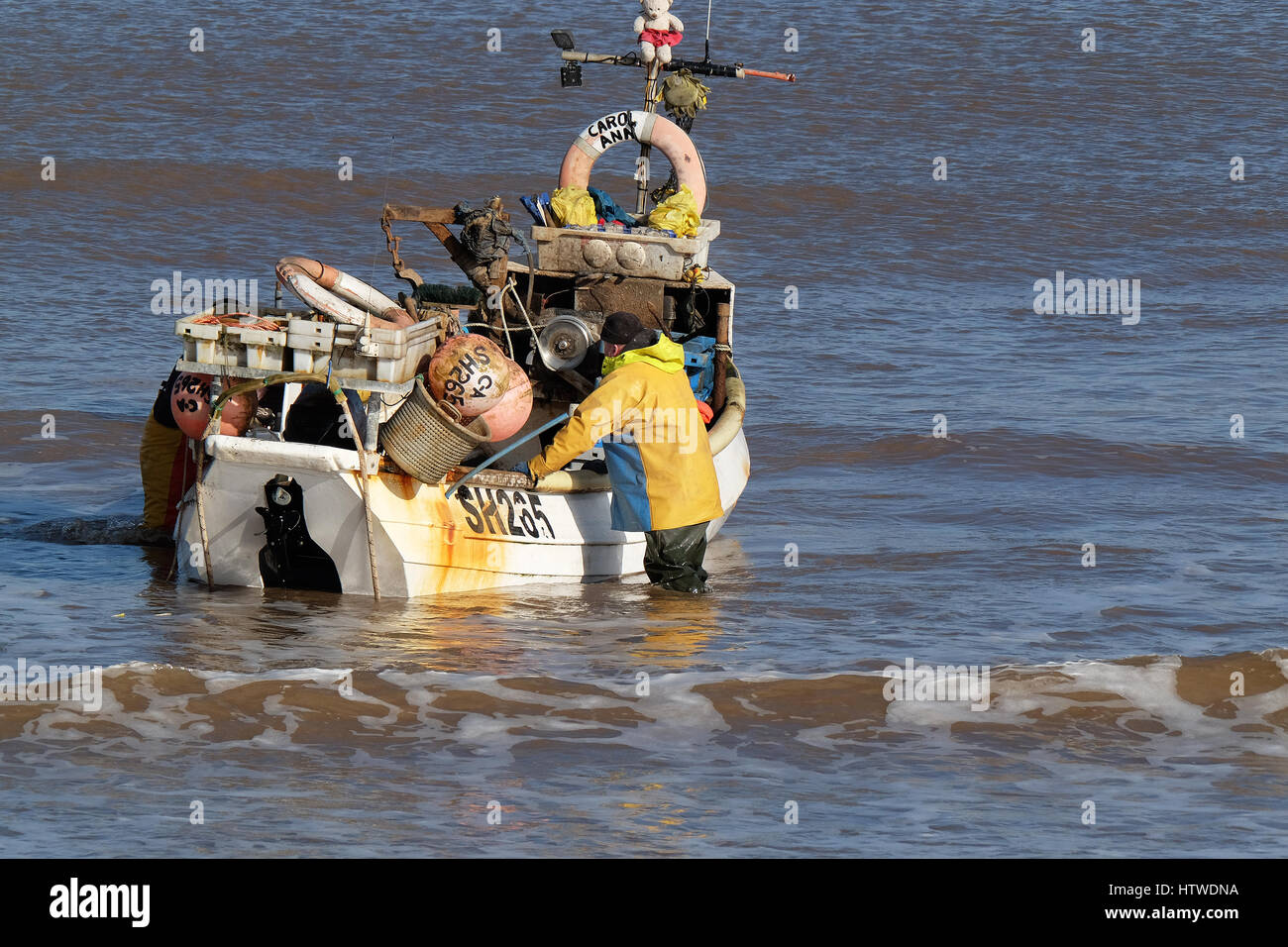 Small shell fishing boat with two man crew returning to beach at ...