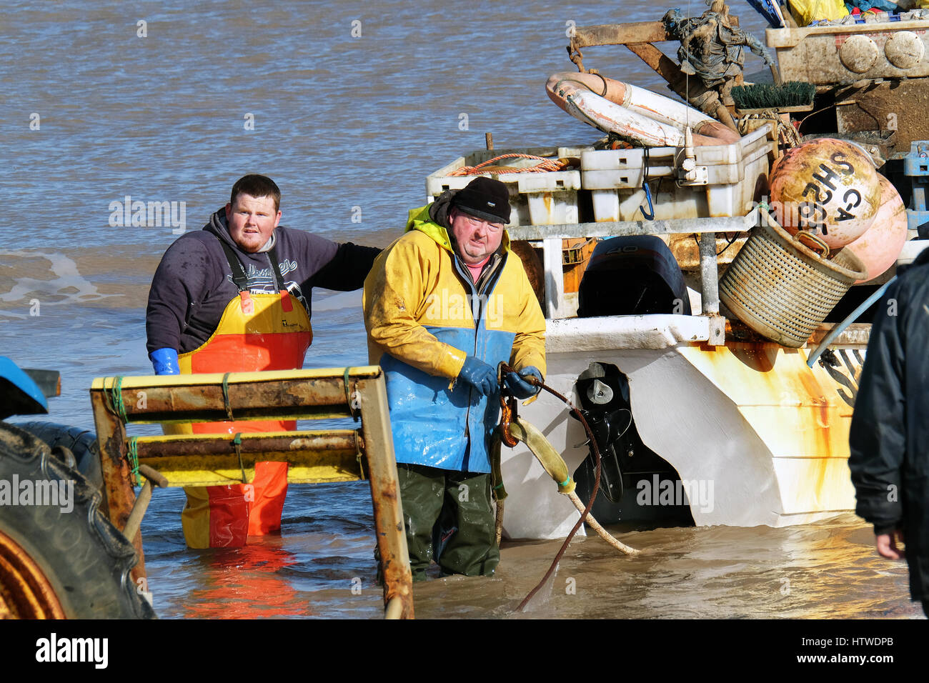 Small shell fishing boat with two man crew returning to beach at ...