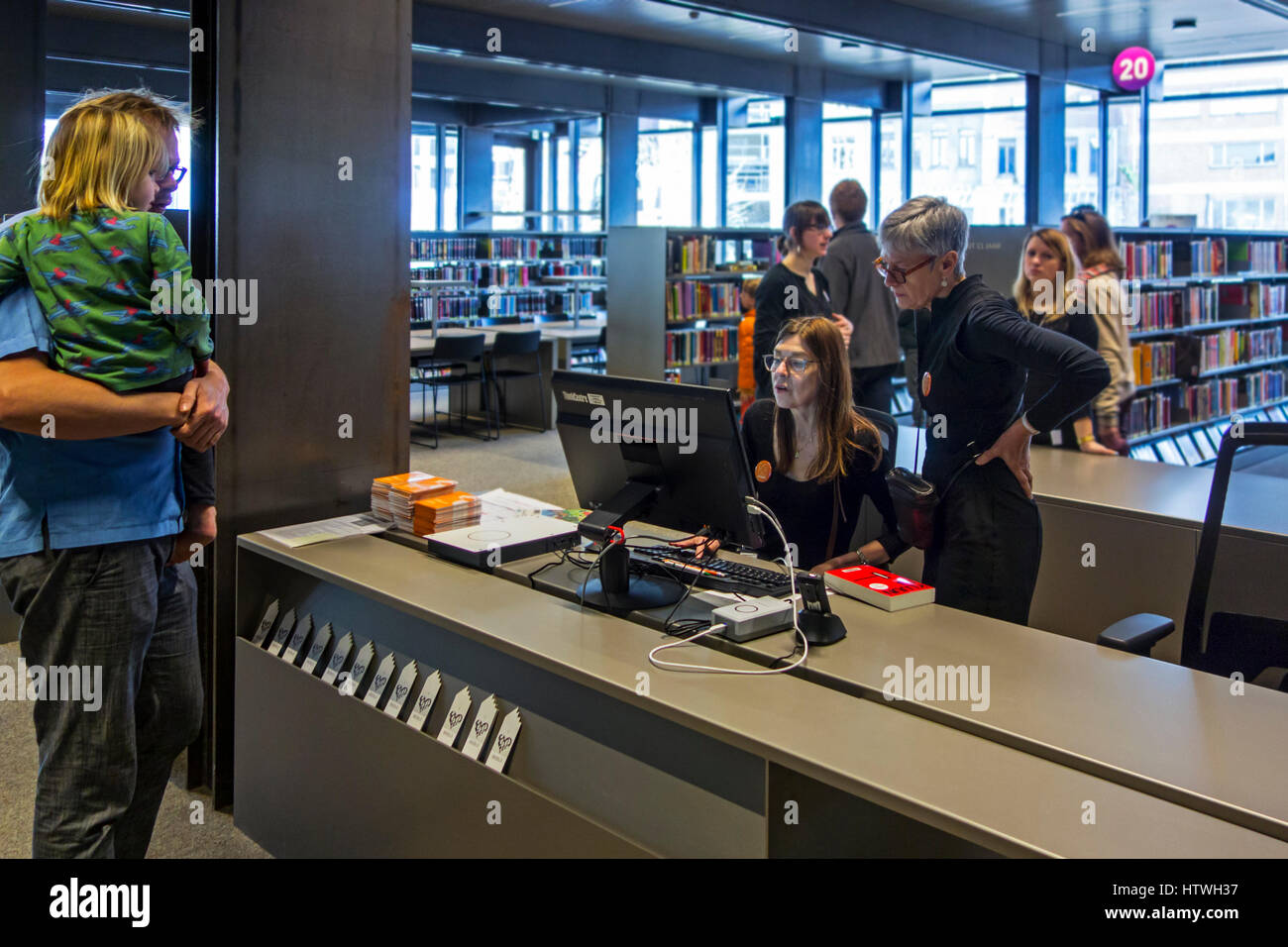 Two female librarians at work behind computer screen in public library ...