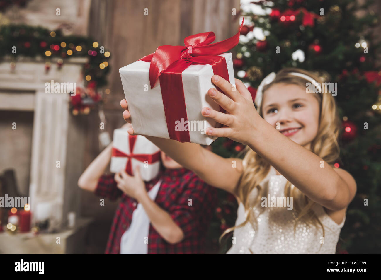 Cute children opening gift boxes on floor near Christmas tree Stock ...