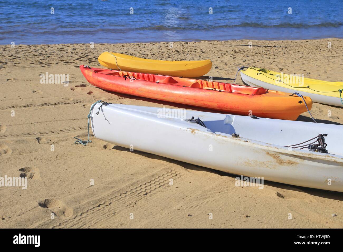 Colorful red, yellow and orange canoes and kayaks on a beautiful sandy ...