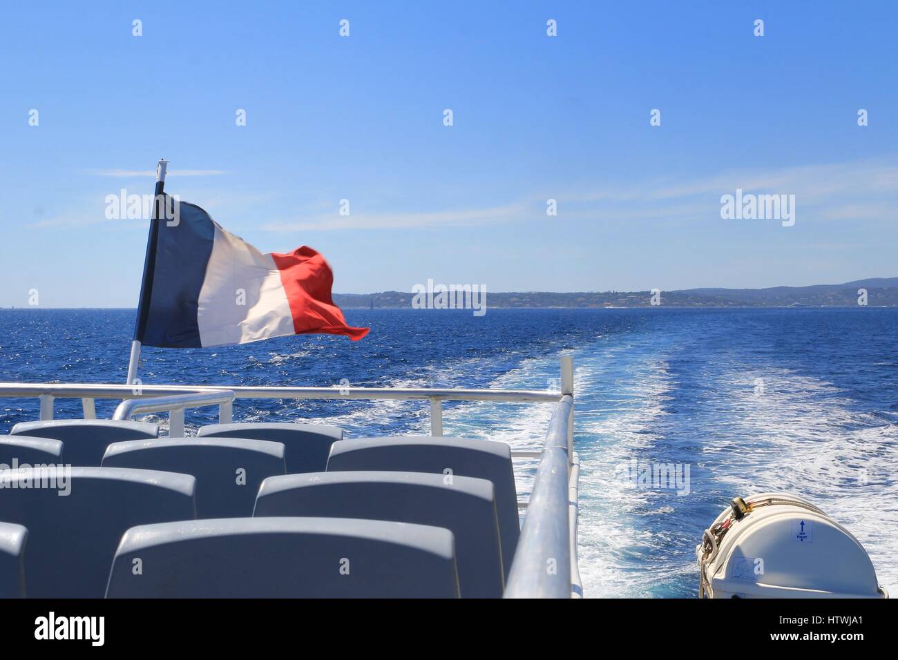 French tricolour flag flying on the back of a boat leaving a wake ...