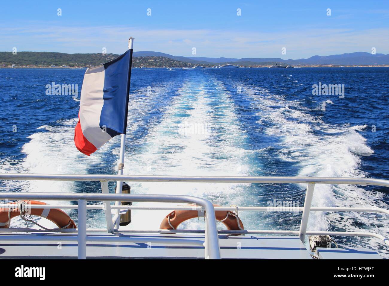 French tricolour flag flying on the back of a boat leaving a wake ...