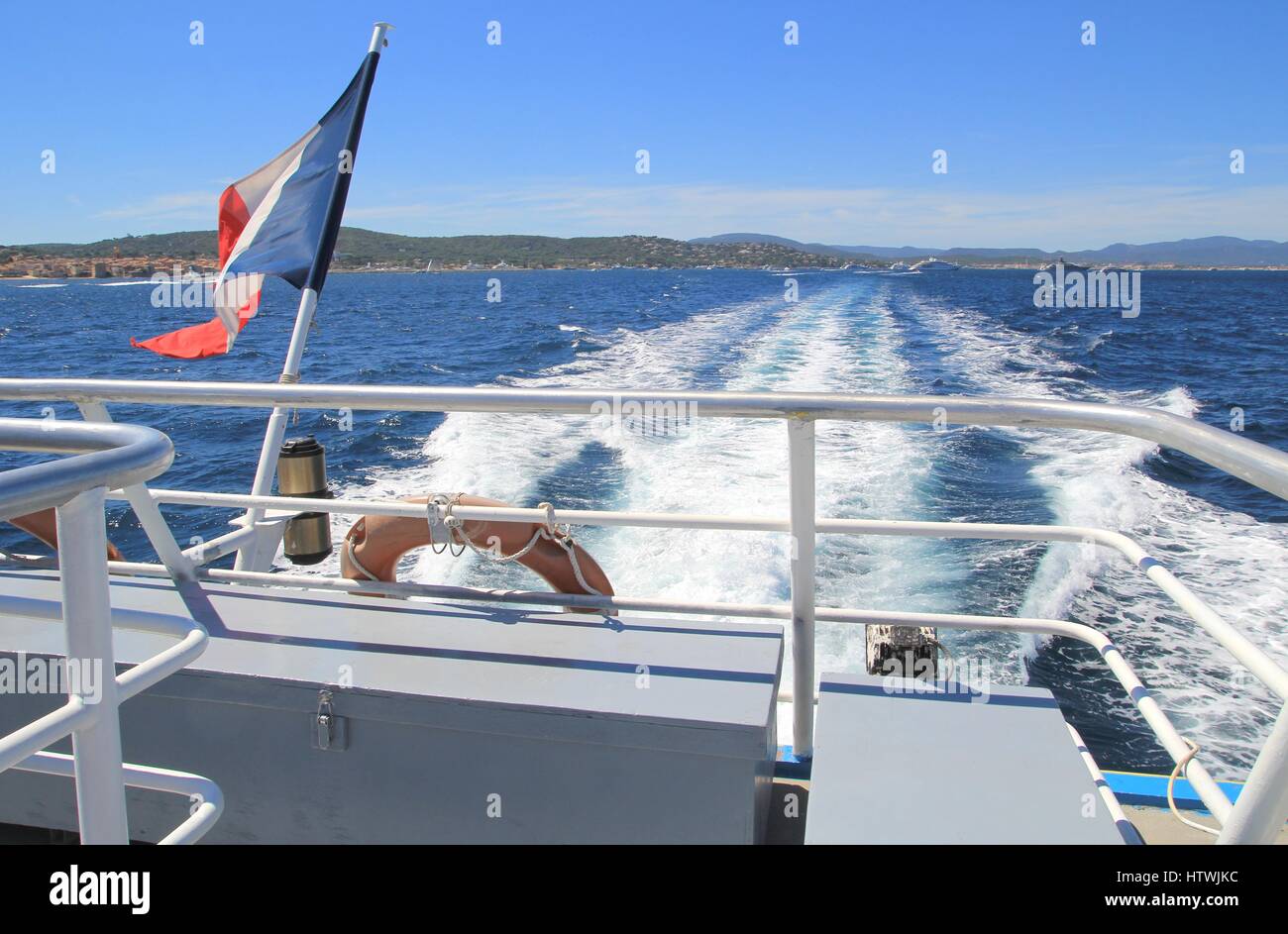 French tricolour flag flying on the back of a boat leaving a wake ...