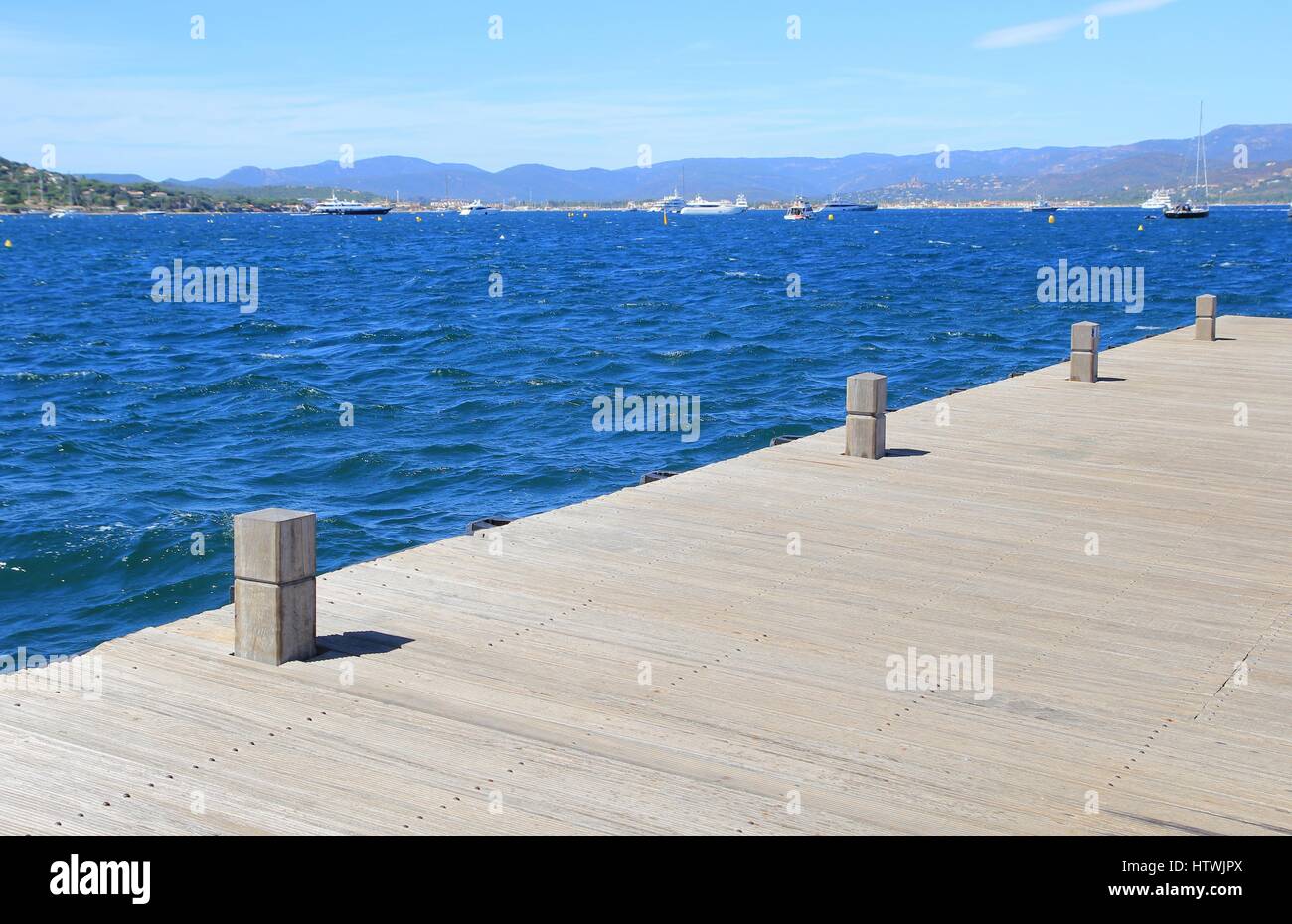 wooden boat mooring bollards on jetty by blue ocean Stock Photo - Alamy