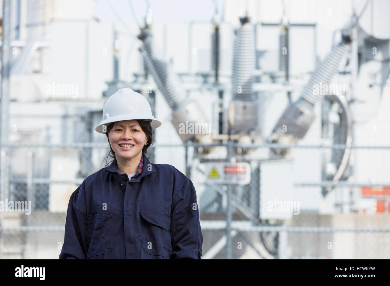 Portrait of female power engineer in front of high voltage transformer ...
