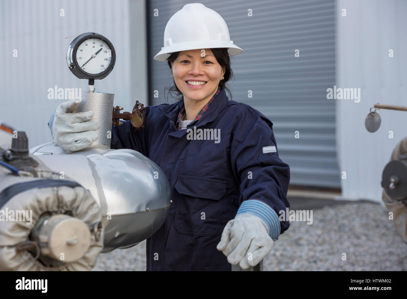 Portrait of female power engineer with pressure sensor at power station ...