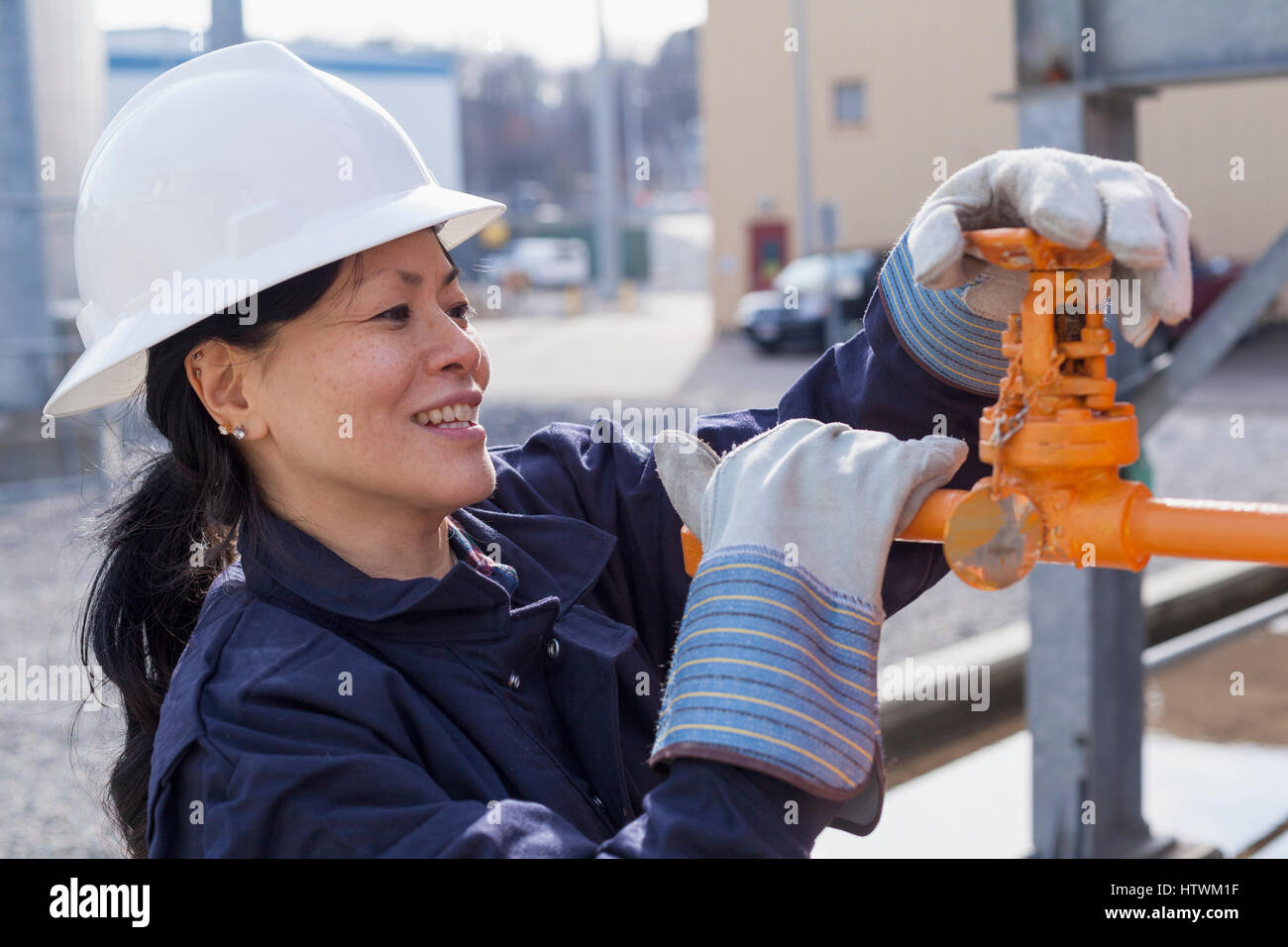 Female power engineer checking valve at power station Stock Photo - Alamy