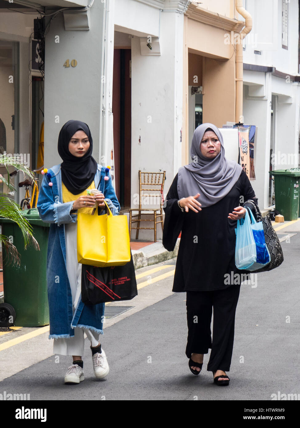 Two Muslim women carrying shopping bags walking along Haji Lane ...