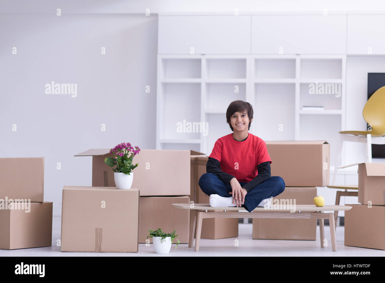 happy little boy sitting on the table with cardboard boxes around him ...