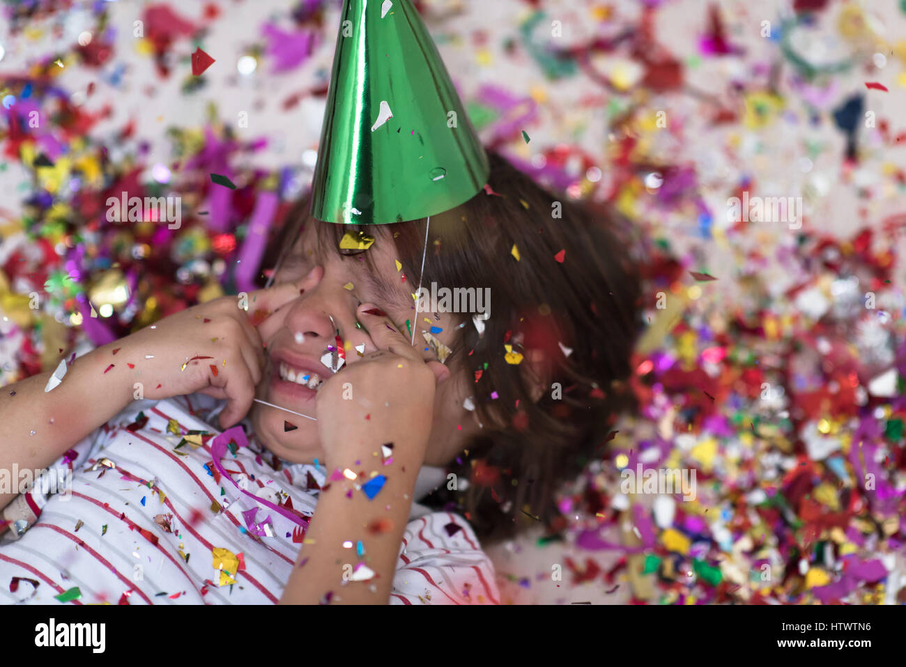 Happy kid celebrating party with blowing confetti while lying on the ...