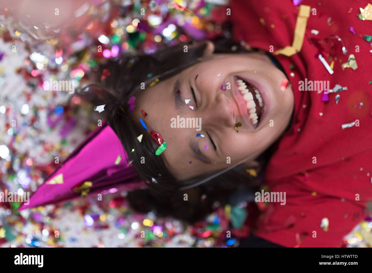 Happy kid celebrating party with blowing confetti while lying on the ...