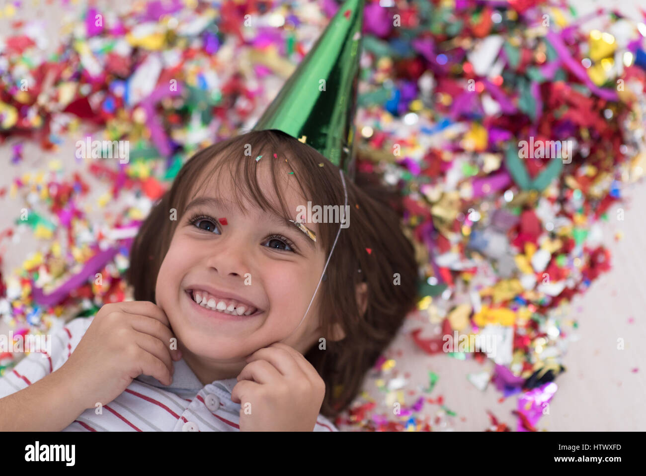 Happy kid celebrating party with blowing confetti while lying on the ...