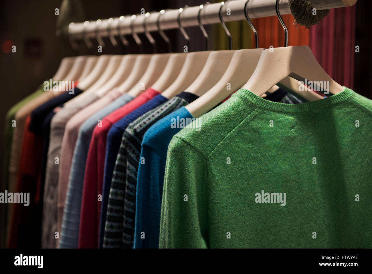 Color sweaters on a rack in a boutique store Stock Photo - Alamy