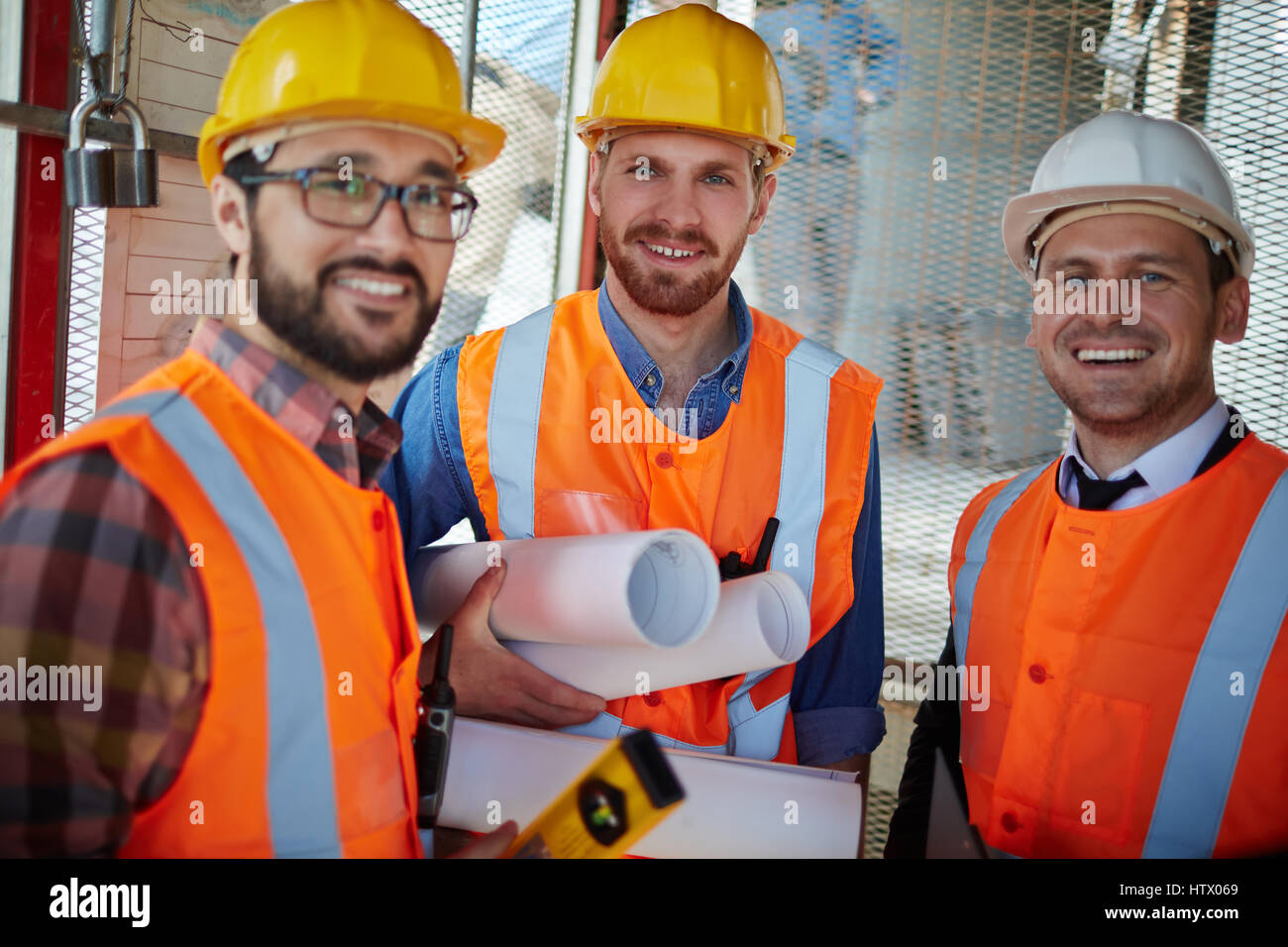 Three constructors on construction-site looking at camera Stock Photo ...