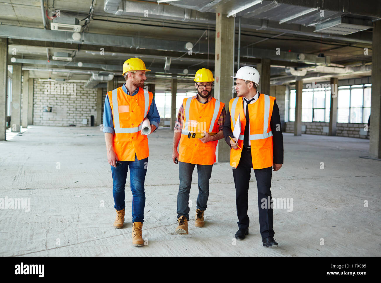 Group of contractors walking down concrete floor of unfinished ...