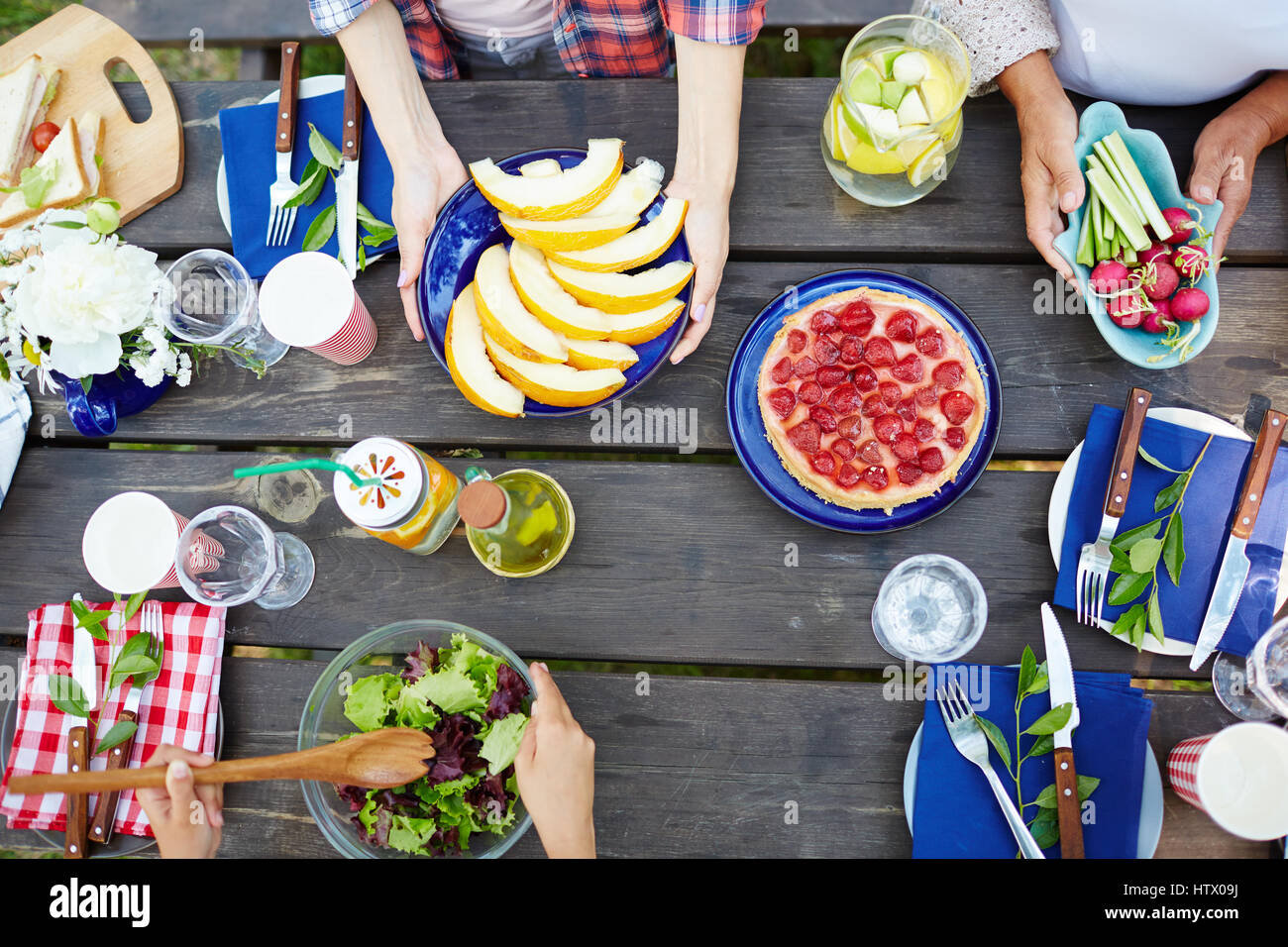 Group of humans serving wooden table for dinner Stock Photo - Alamy