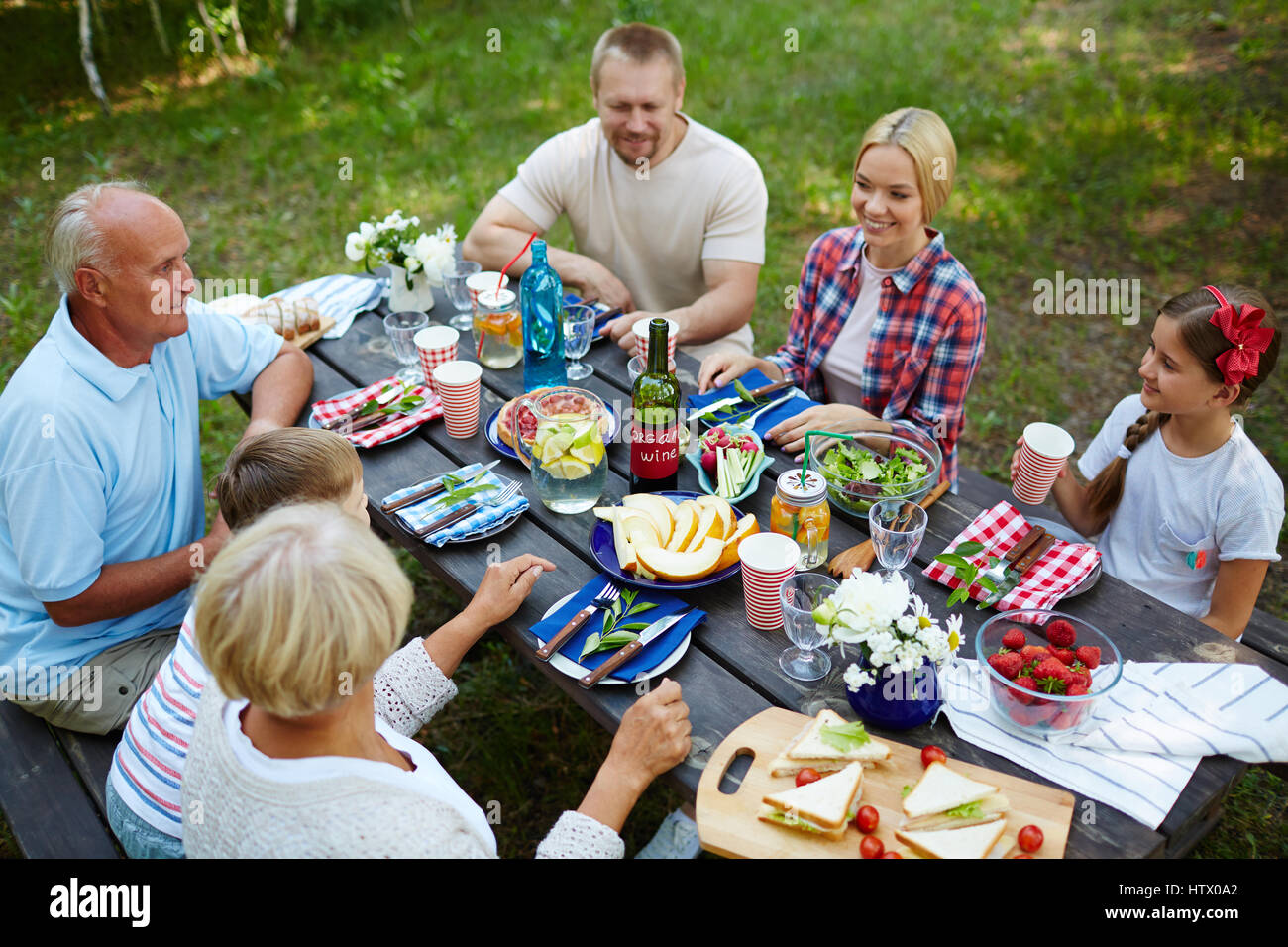 Three generations having dinner by served table outdoors Stock Photo ...
