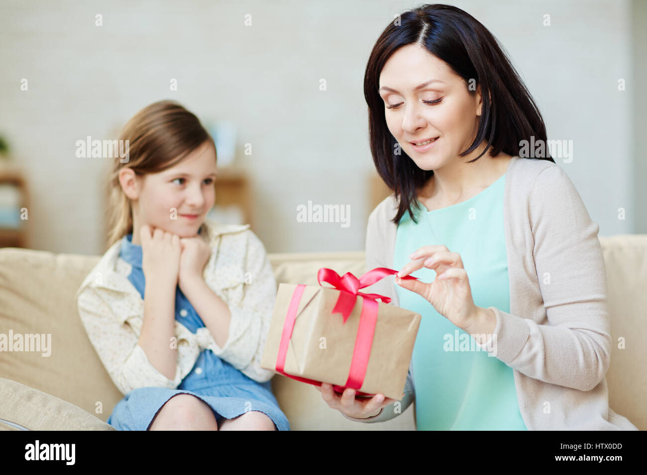 Pretty young female unpacking gift of her daughter Stock Photo - Alamy