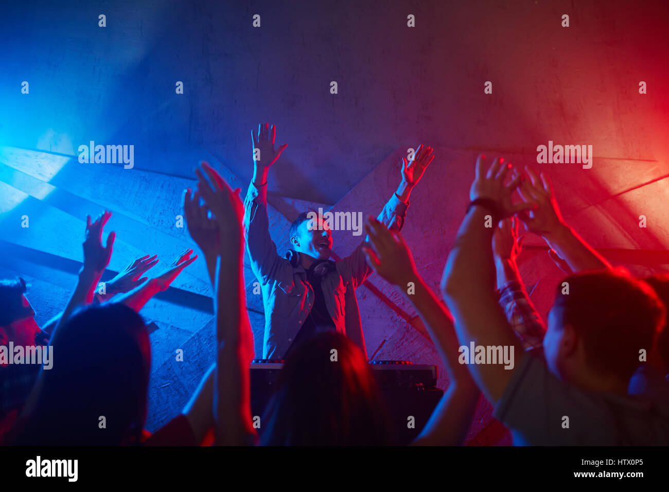 Happy deejay entertaining youthful audience at night Stock Photo - Alamy