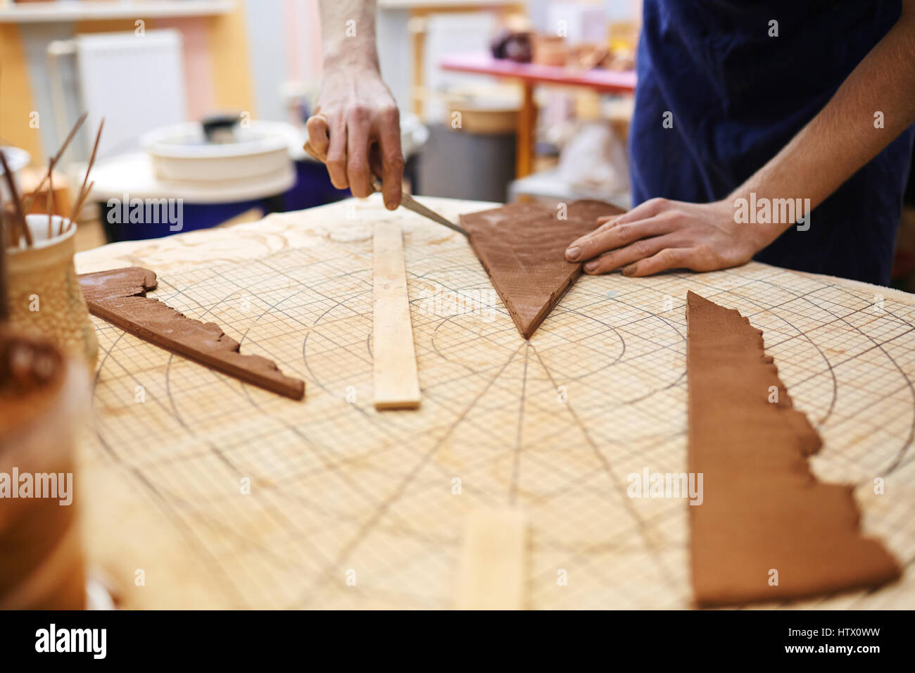 Professional potter using paper diagram while cutting clay workpiece ...