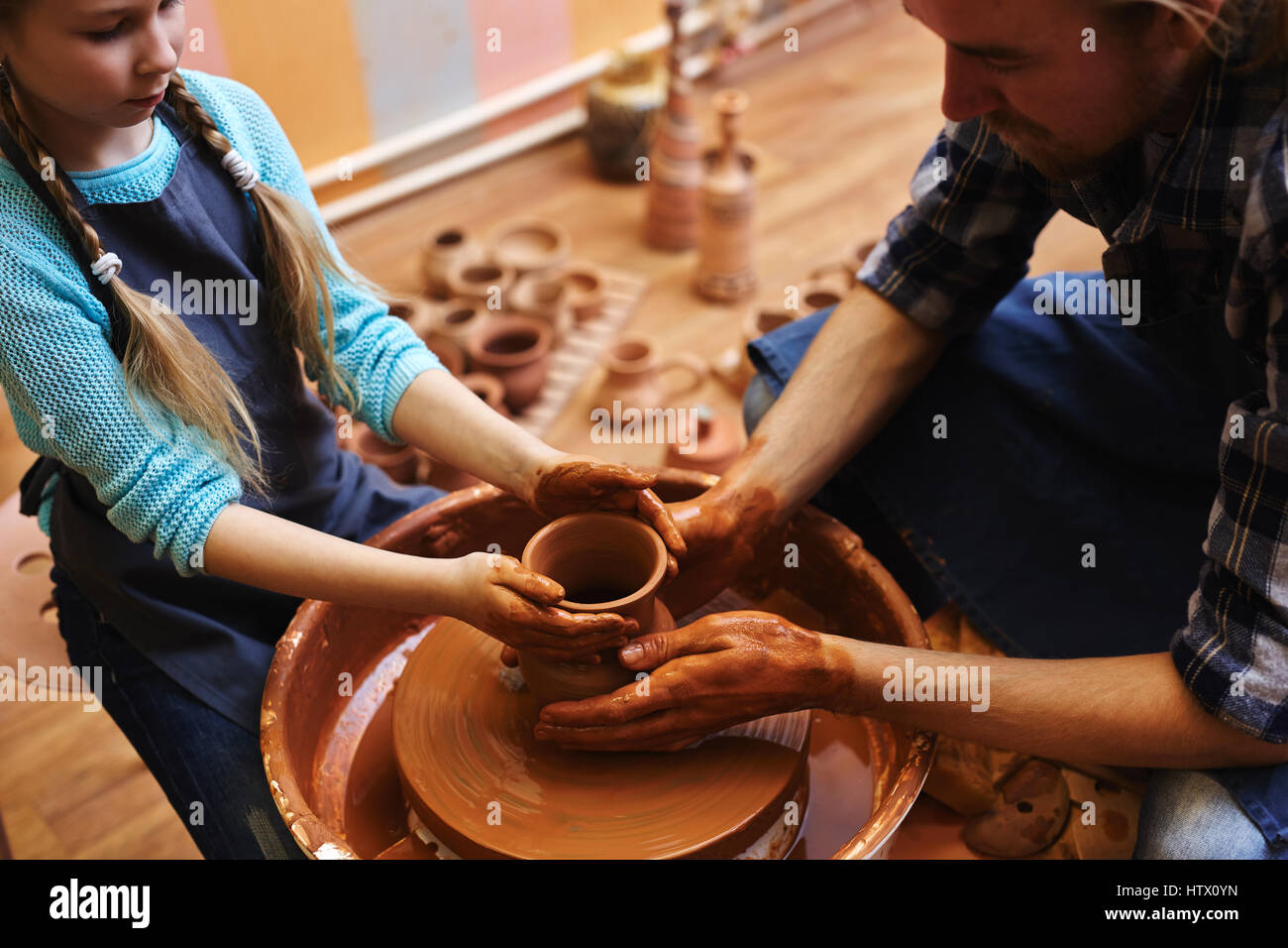 Craftsman and his daughter touching rotating jug in pottery-wheel Stock ...