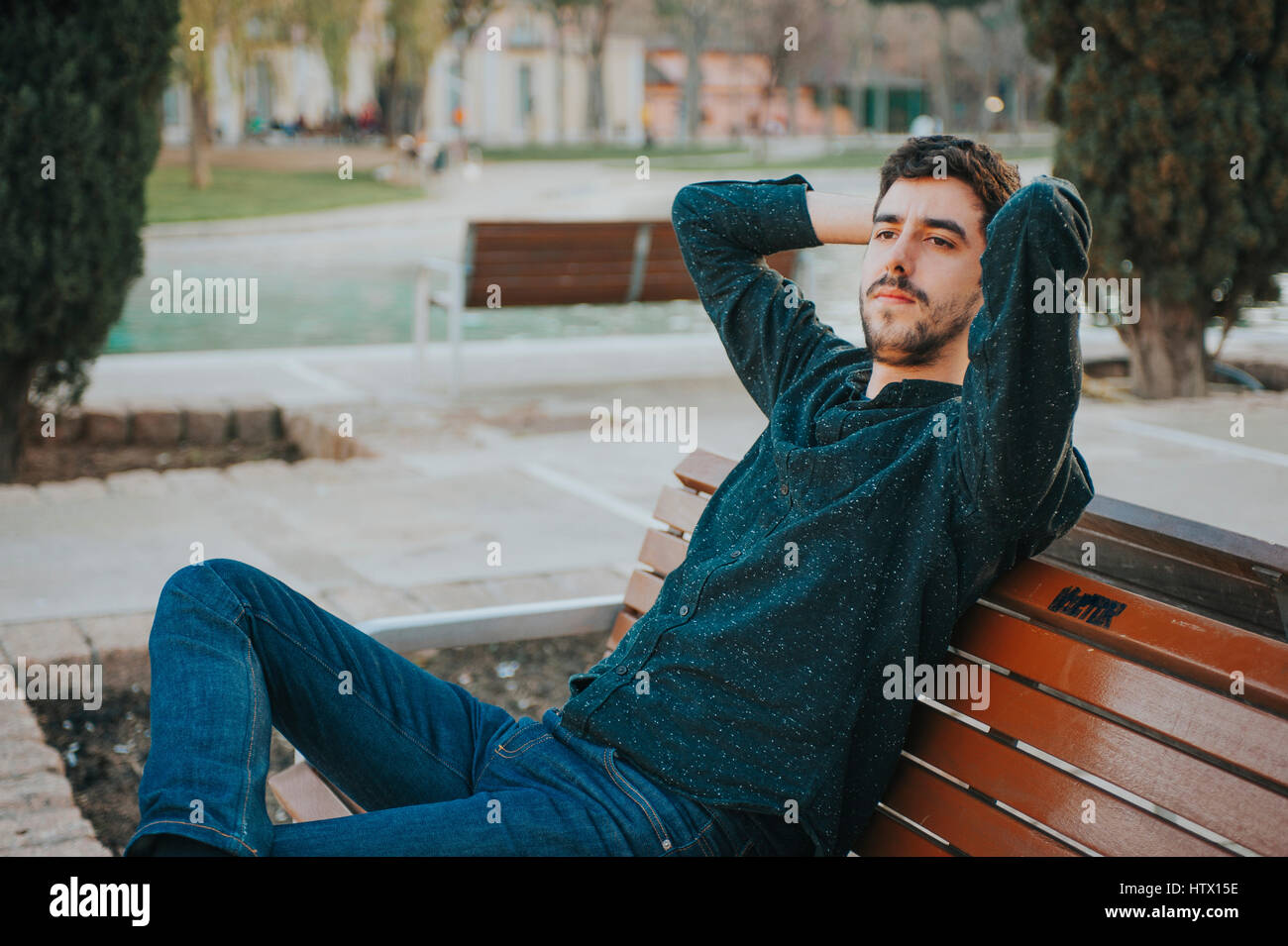 young mexican man sitting in a bench in a park Stock Photo - Alamy