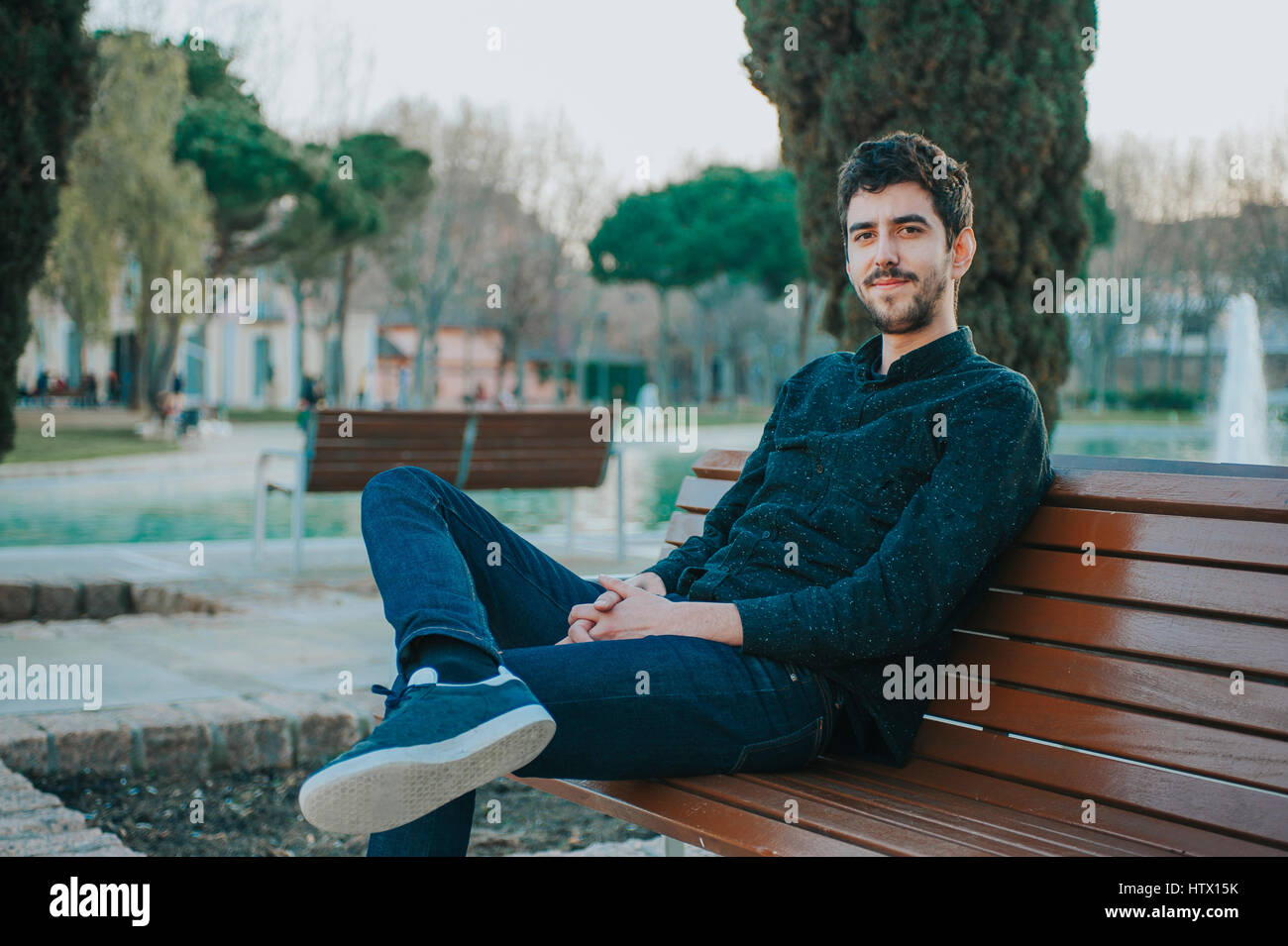 young mexican man sitting in a bench in a park Stock Photo - Alamy