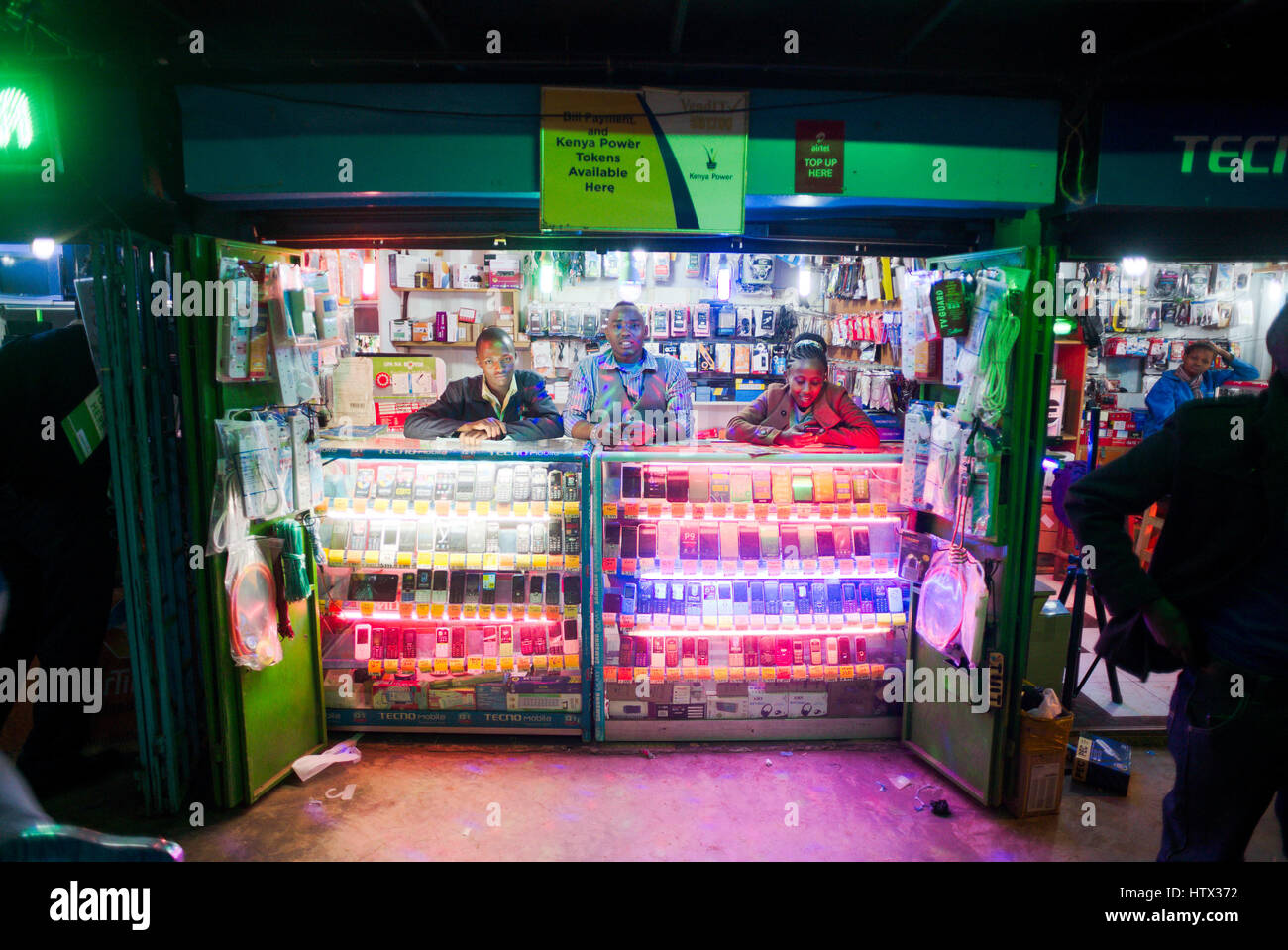 Three shop assistants sell phones at their colourful mobile shop in ...