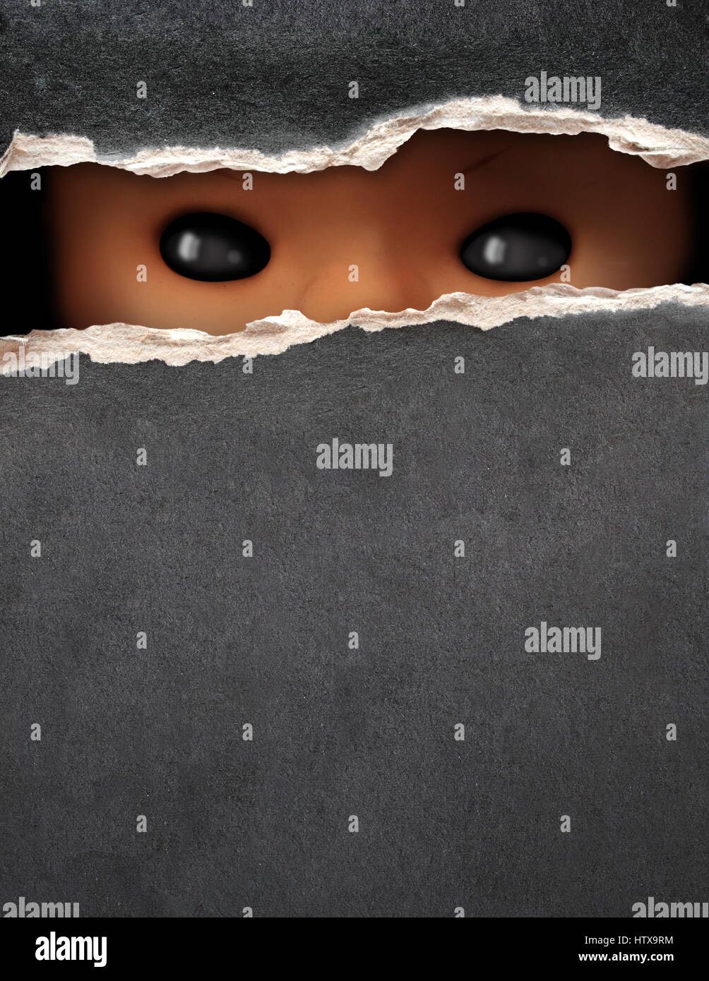 Dark series - a look from darkness. Eyes of spooky doll in paper hole ...