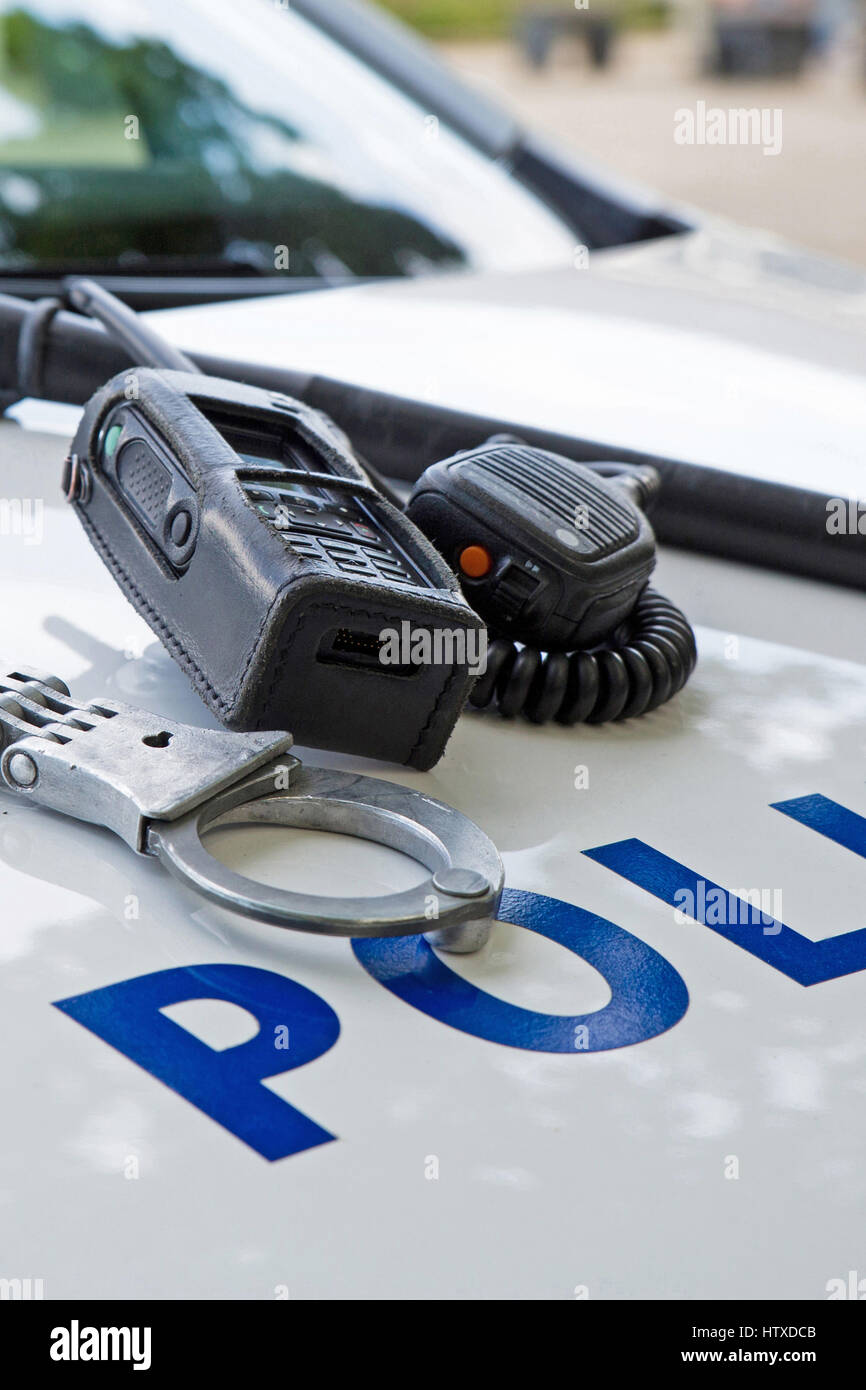 Police equipment on a police car. Handcuffs, baton and pager on top of ...