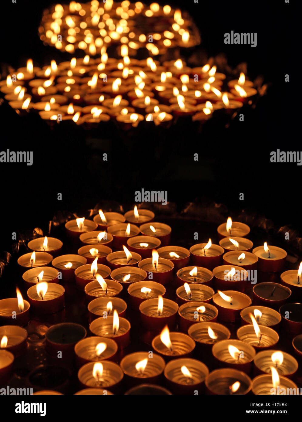 many candles lit with the warm flame during the religious ceremony ...