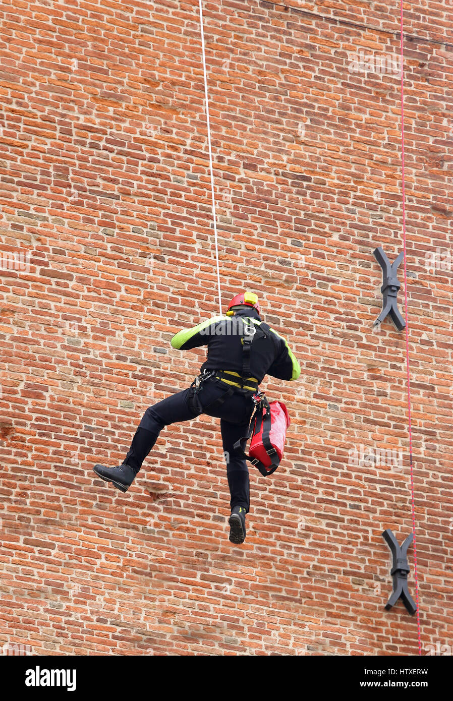 brave firefighter during a training exercise climbing on old brick ...