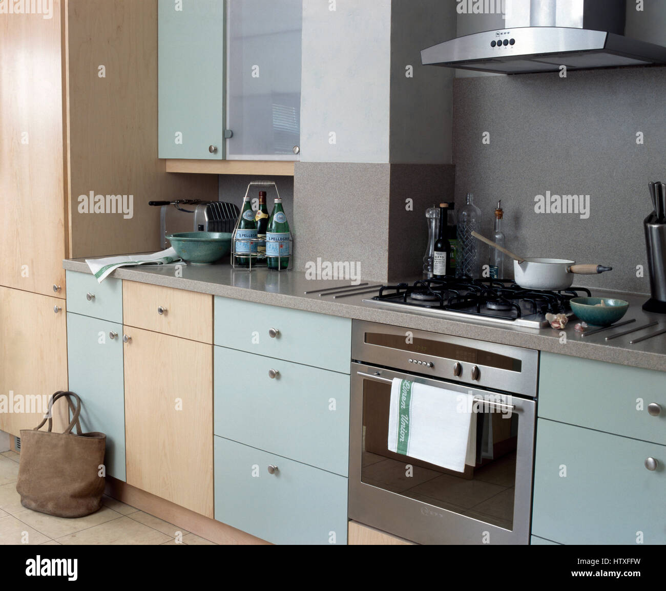 Plain pale wood and pale blue fitted units in a modern grey kitchen ...