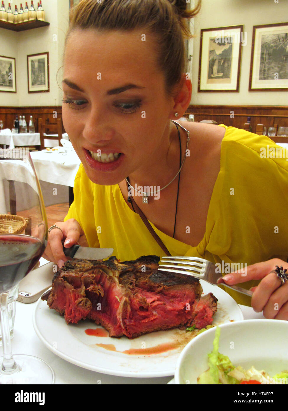 hungry woman eats Florentine fiorentina meat at the restaurant table ...