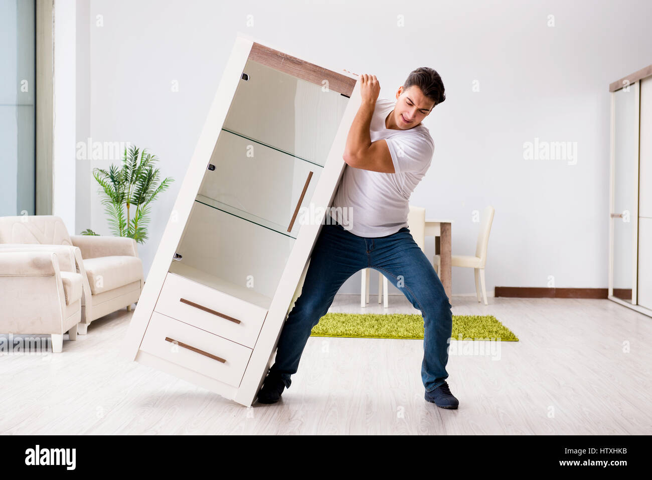 Young man moving furniture at home Stock Photo - Alamy