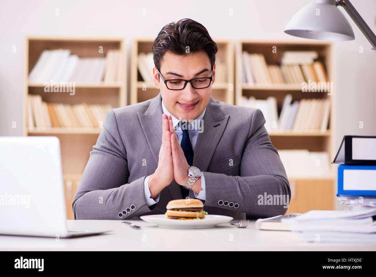 Hungry funny businessman eating junk food sandwich Stock Photo - Alamy