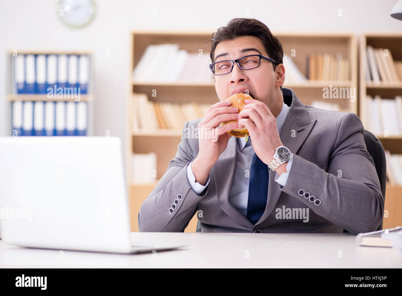 Hungry funny businessman eating junk food sandwich Stock Photo - Alamy