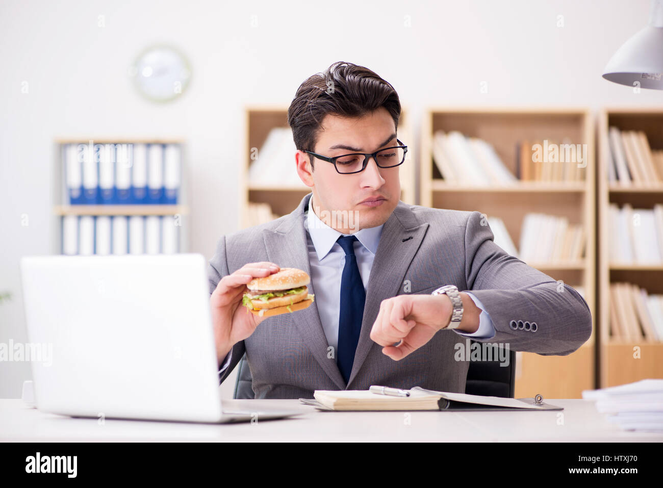 Hungry funny businessman eating junk food sandwich Stock Photo - Alamy