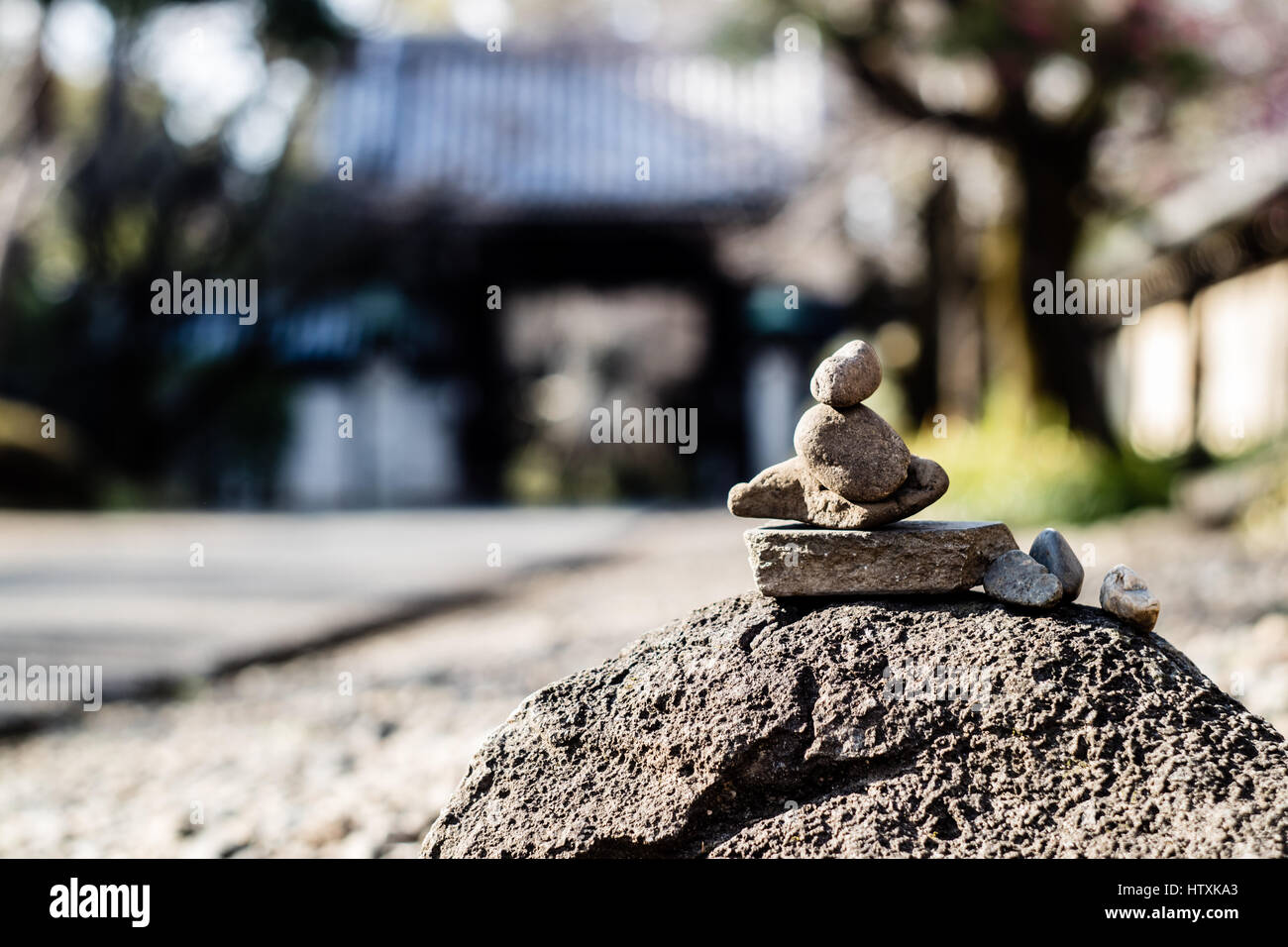 A stack of pebbles precariously balanced in front of a Japanese shrine ...