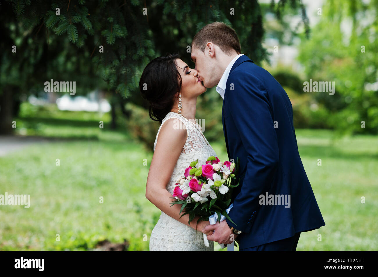 Happy stylish loved couple kisses in love at green spring background ...