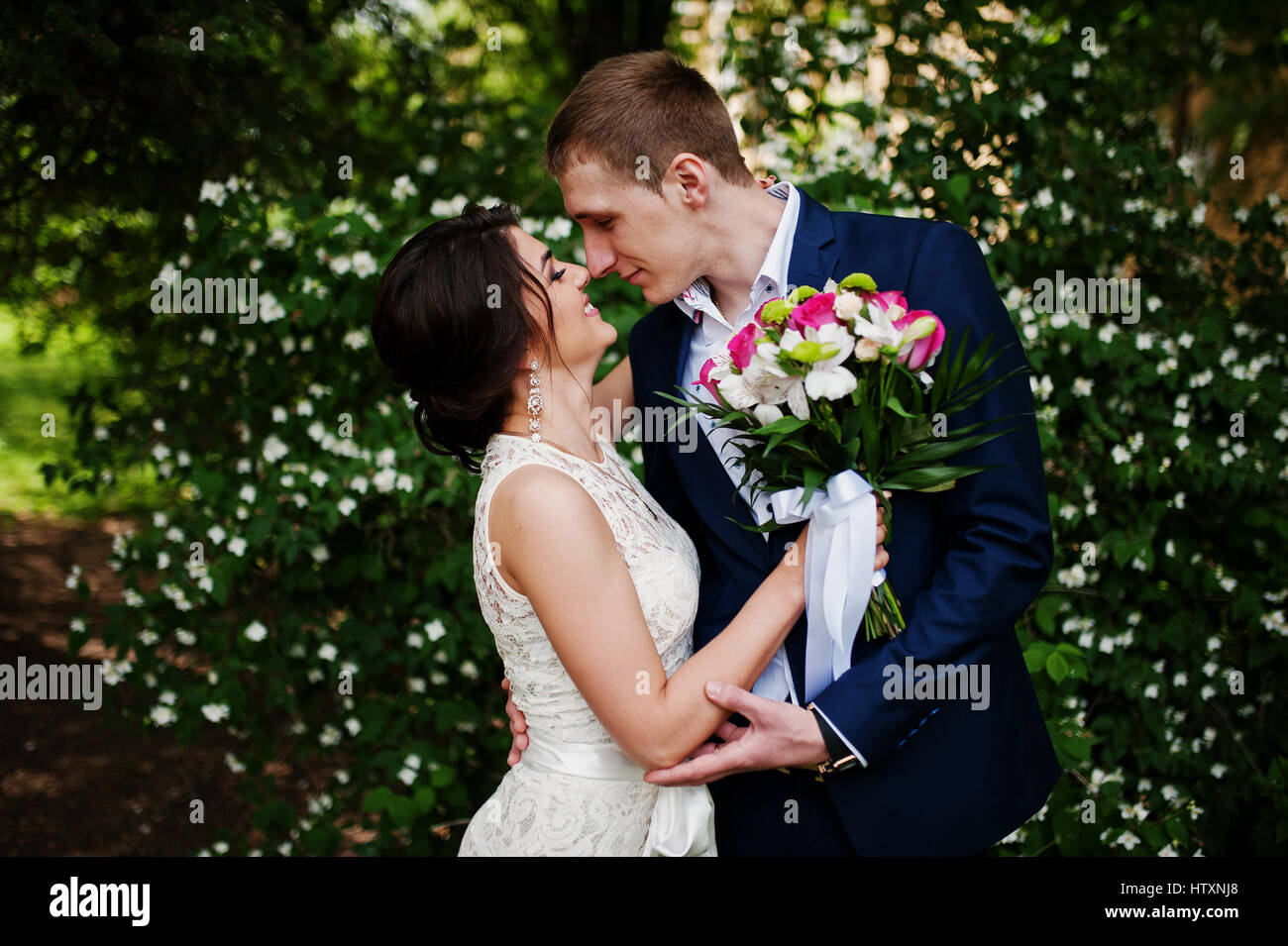 Happy stylish loved couple kisses in love at green spring background ...