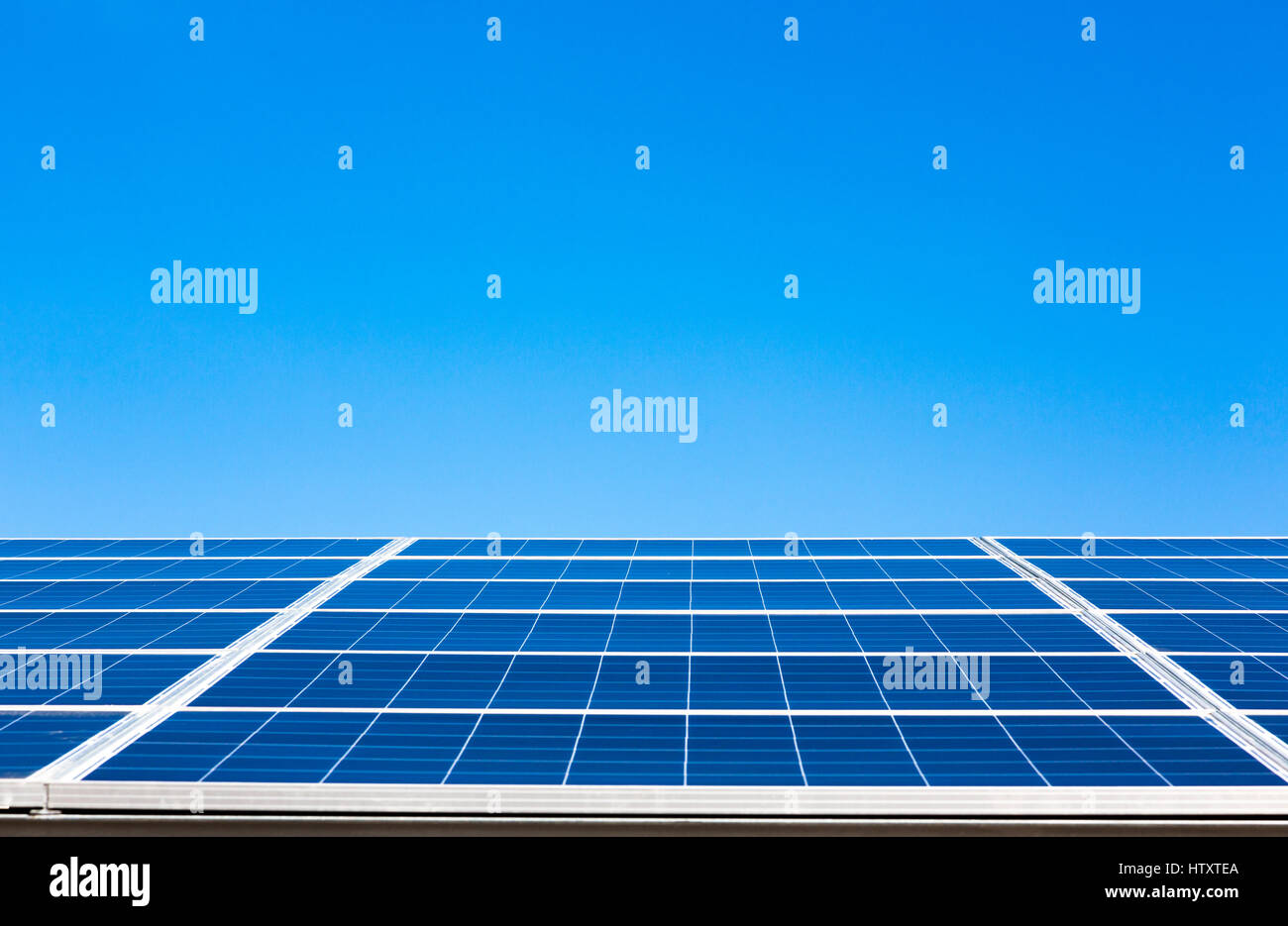 Bright blue solar panels on blue clear sky background in sunny weather ...