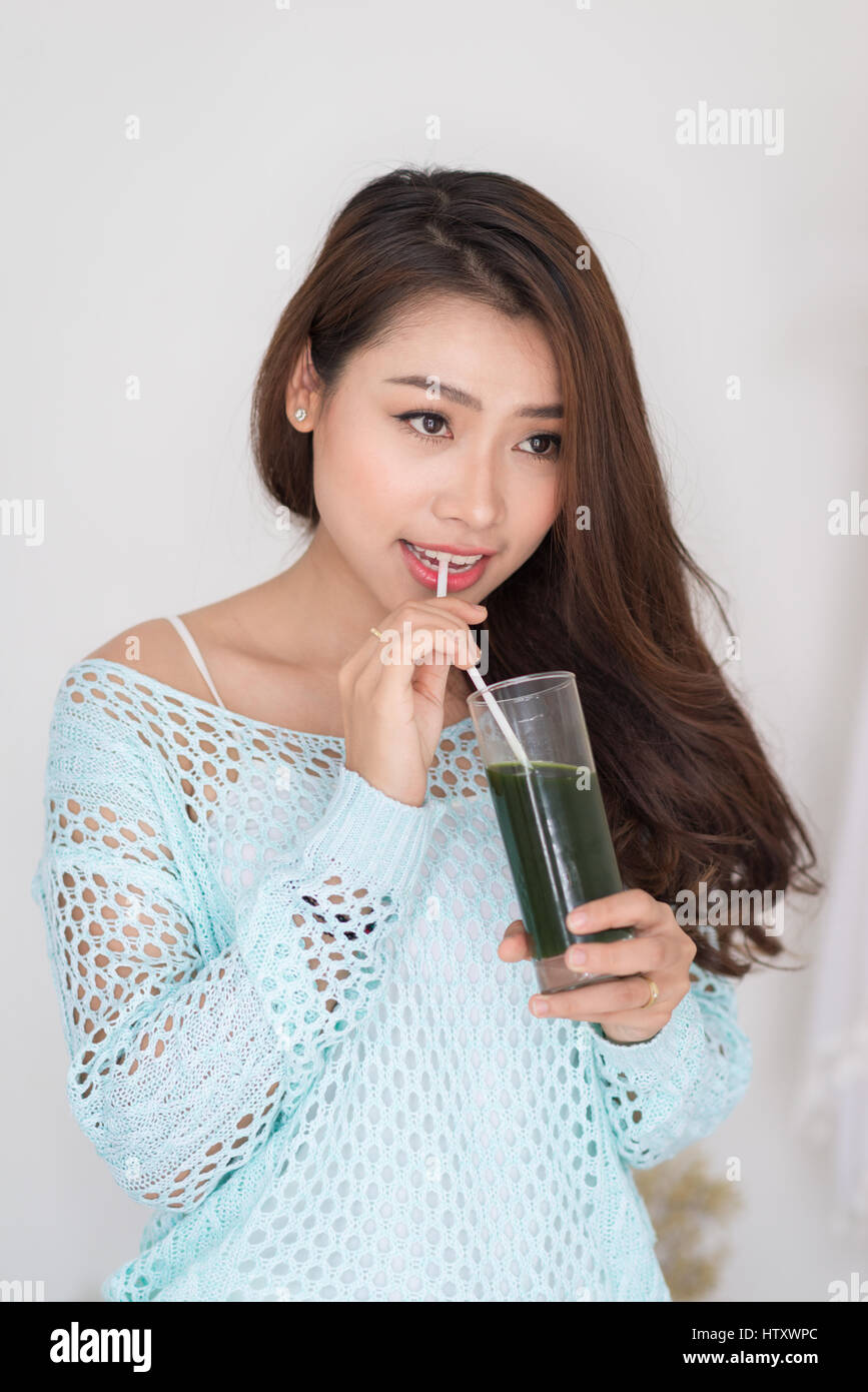 Smiling Young Asian Woman Drinking Green Fresh Vegetable Juice Or
