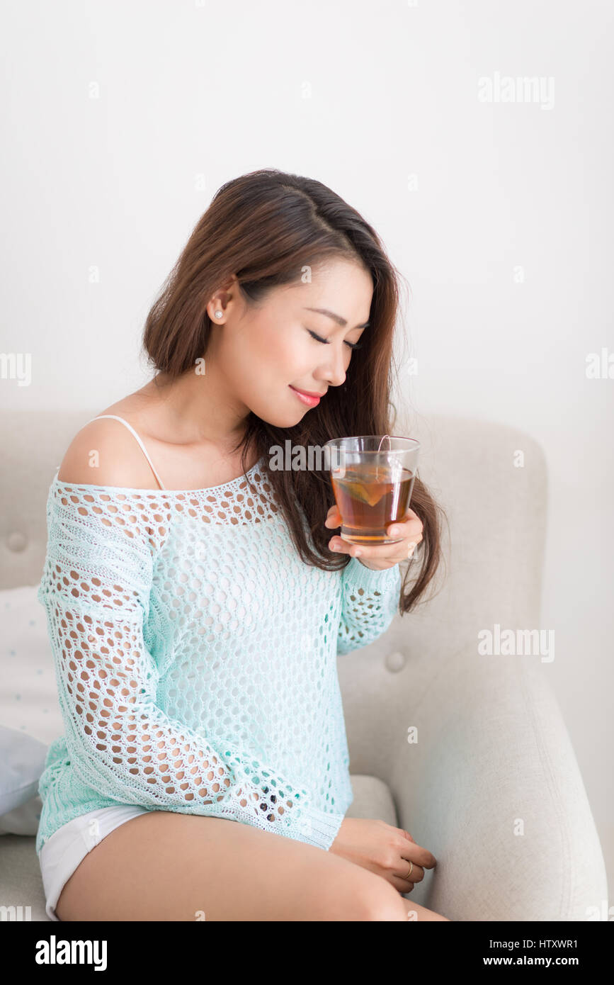 Beautiful young asian woman drinking her morning tea over a breakfast ...